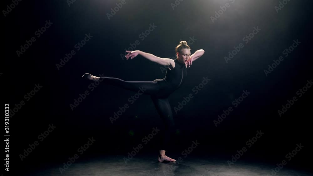 Pretty young actress performing expressive dance elements against black ...
