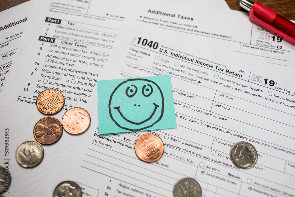 IRS 1040 tax return form with smiley face drawn on a sticker. Wage and ...