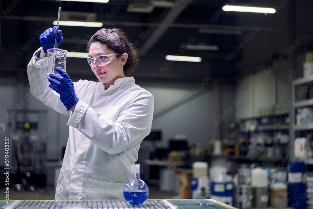 Brunette lab girl in glasses and white coat with experimental glass in ...