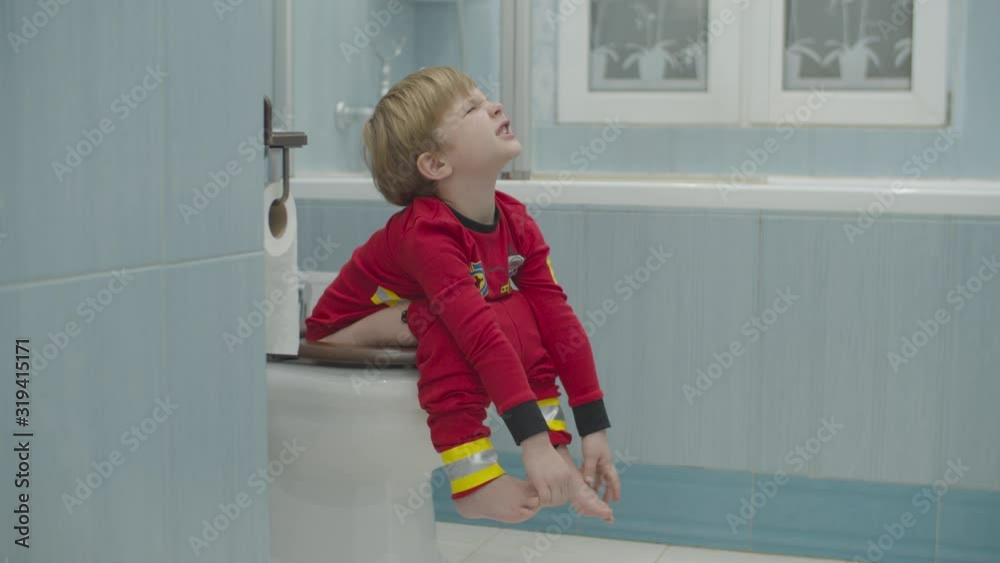 Blond preschool boy in fireman pajamas pushing sitting on toilet in ...