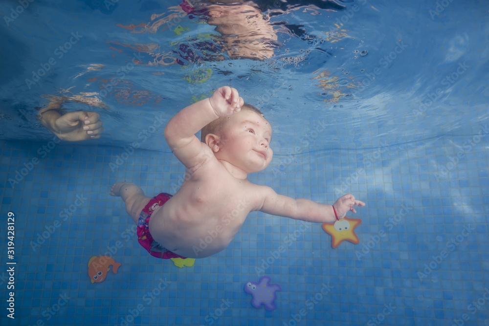 Little baby learns to swims underwater. Baby swimming underwater in the ...