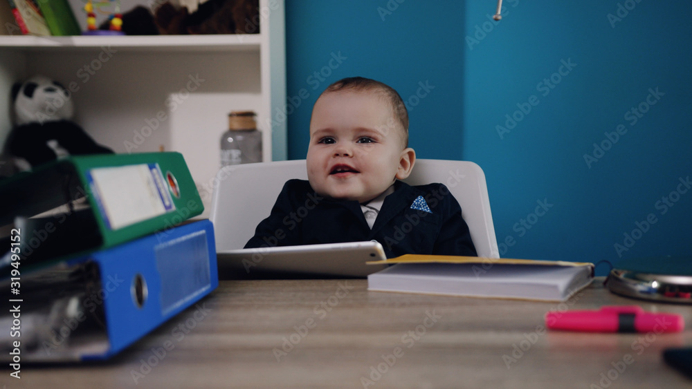 Extremely cute toddler baby boss sits in the office, unrecognizable ...