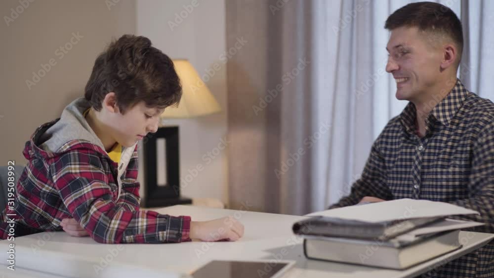 Close-up side view of Caucasian father and son competing in arm ...