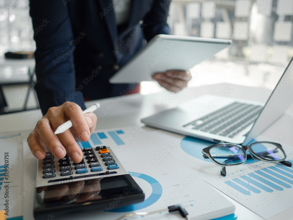 Business woman hand working at a computer, using calculator and laptop ...