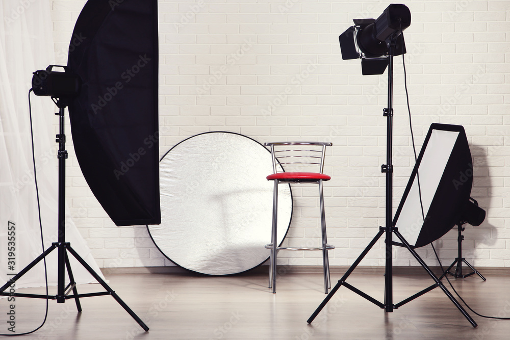 Professional studio equipment and chair on white brick wall background ...