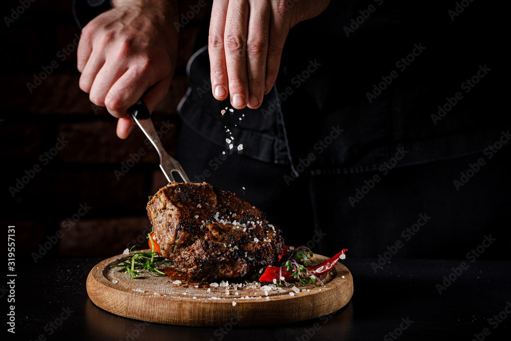 The concept of cooking meat. The chef cook salt on the cooked steak on ...