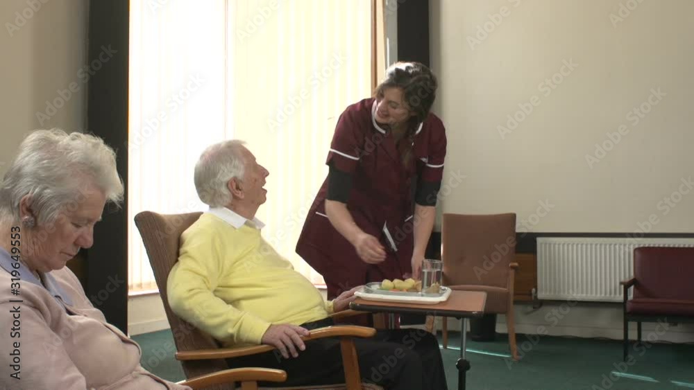 Retirement Home - Care worker brings a tray of food to an Elderly Male ...