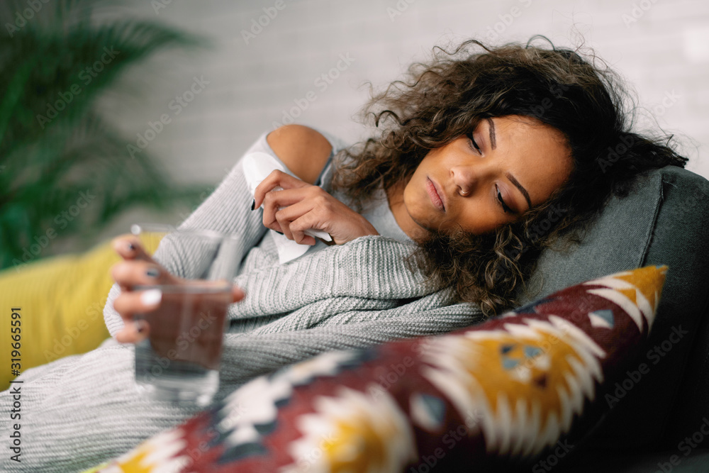 Sick woman at home. Young african woman laying on sofa she is sick ...