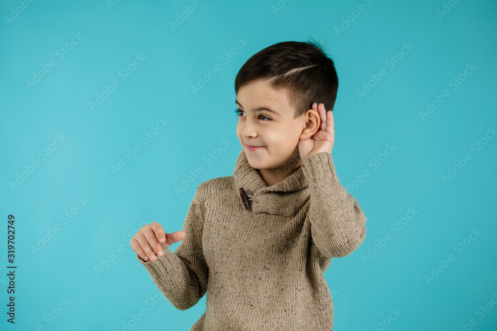 happy little child boy making hearing gesture on blue background ...
