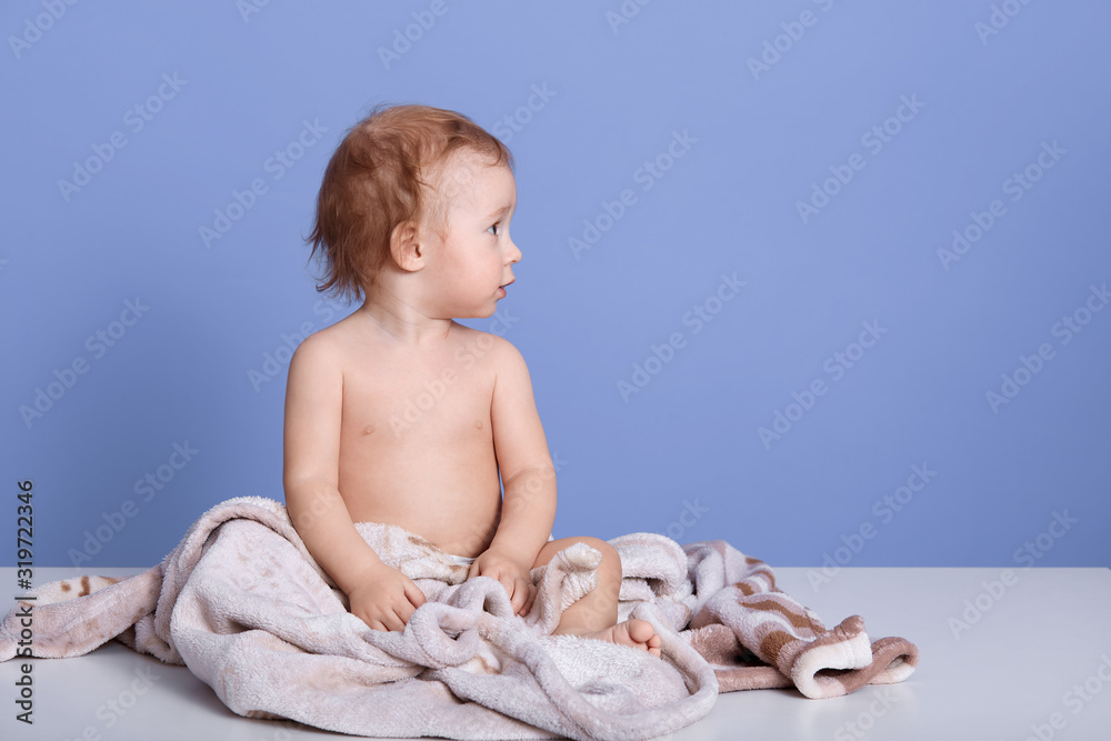 Close up portrait of baby boy sitting on towel, posing bared isolated ...