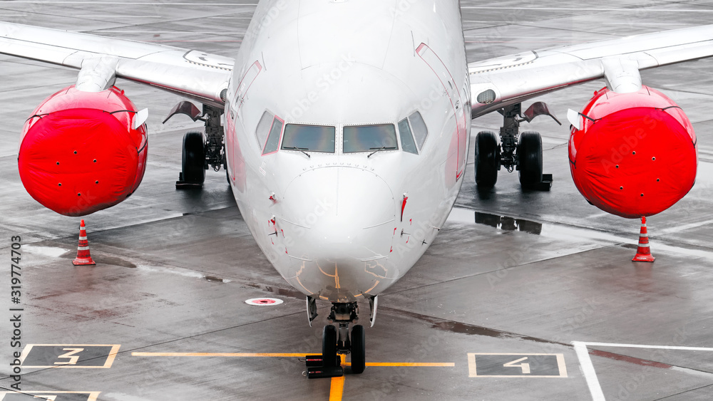modern airplane on airport runway grounded with red jet plane engine ...