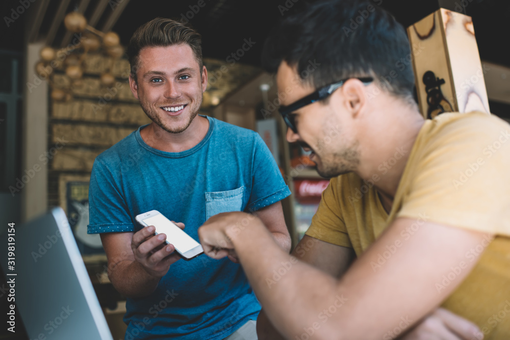 Portrait of cheerful caucasian hipster guy showing his friend new ...