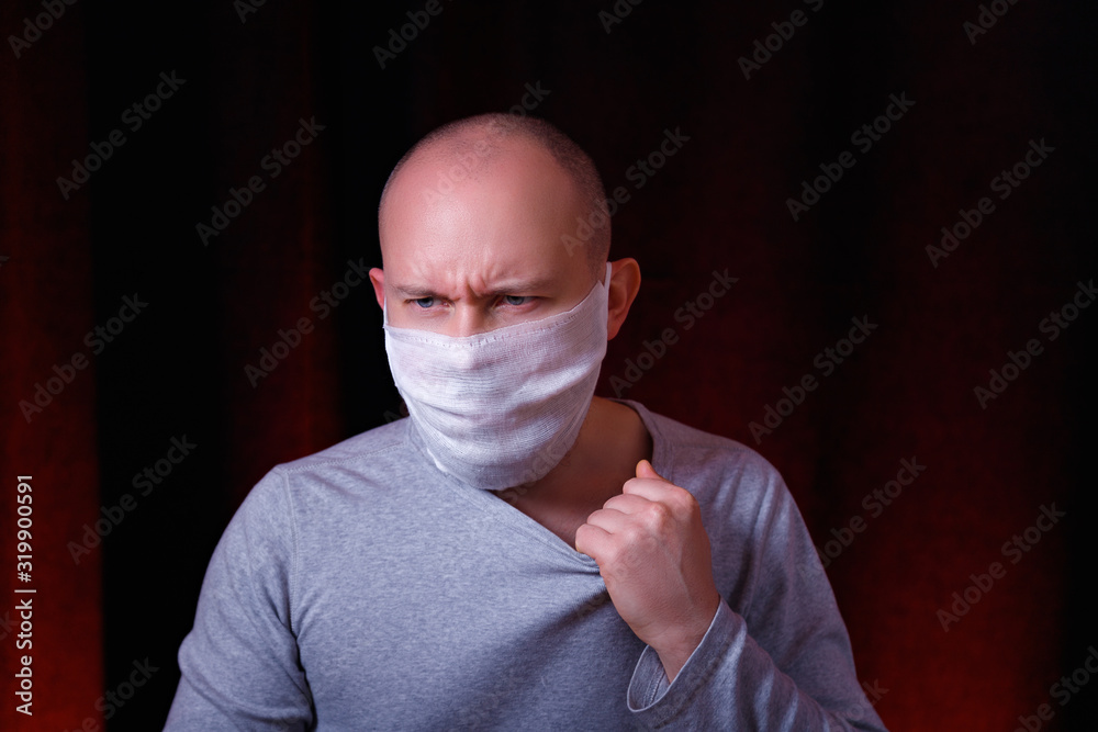 A frowned man with emotion of pain in medical gauze mask standing on ...