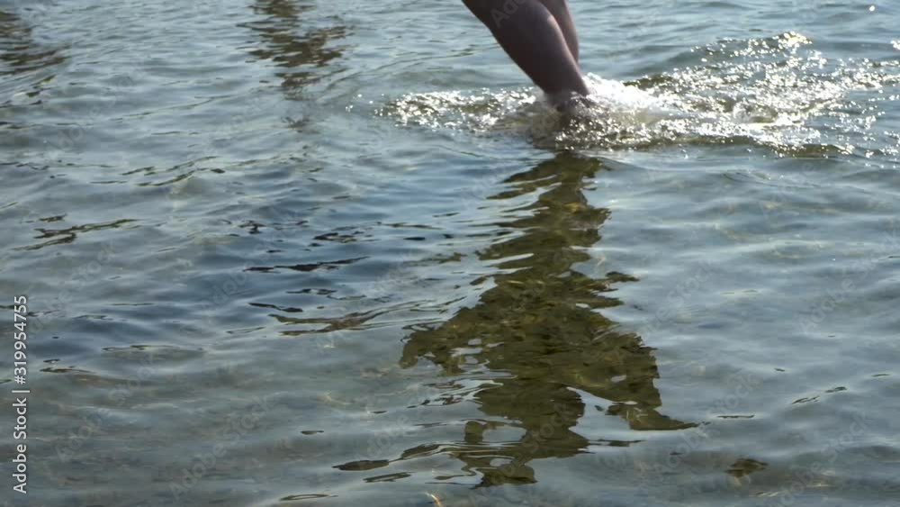 Walk in shallow water. Side view of a barefoot resting man walking ...