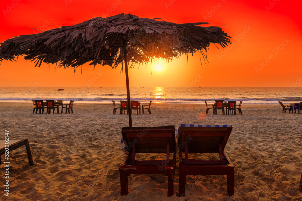Sunset at tropical beach with lounge chairs and beach umbrellas in GOA ...