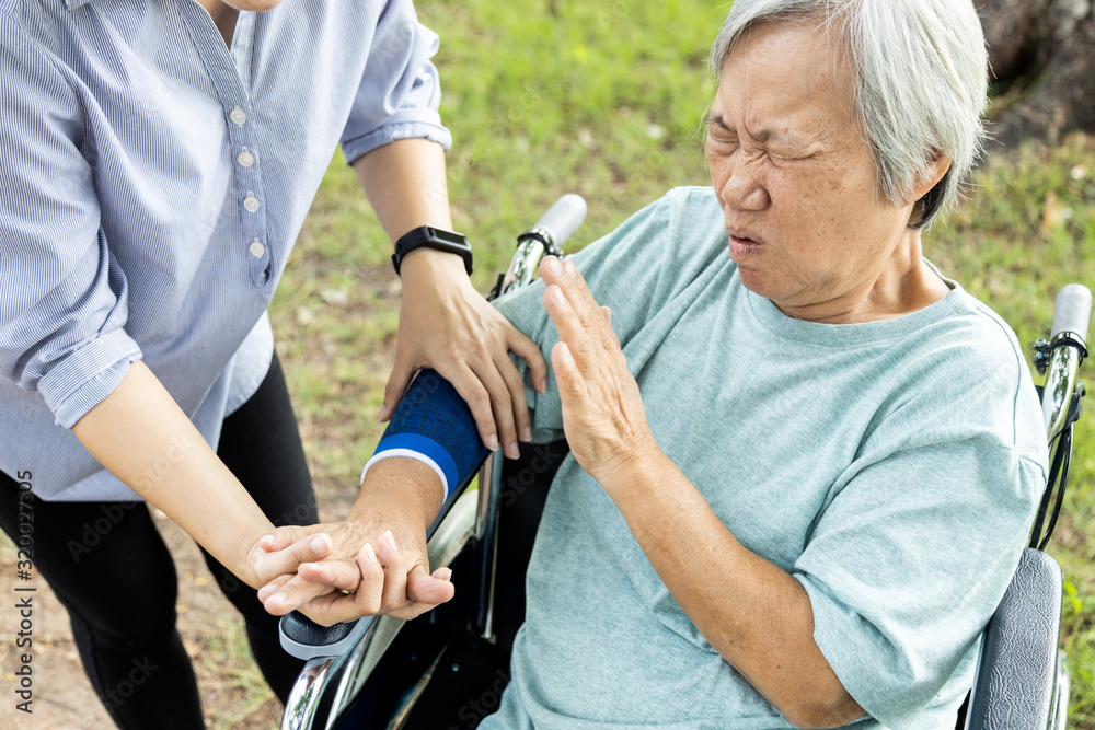 Injured asian senior woman wearing elbow support suffering from ...