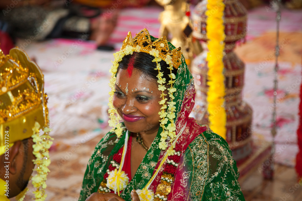 A happy bride smiles at her fiance at a wedding ceremony in a Hindu ...