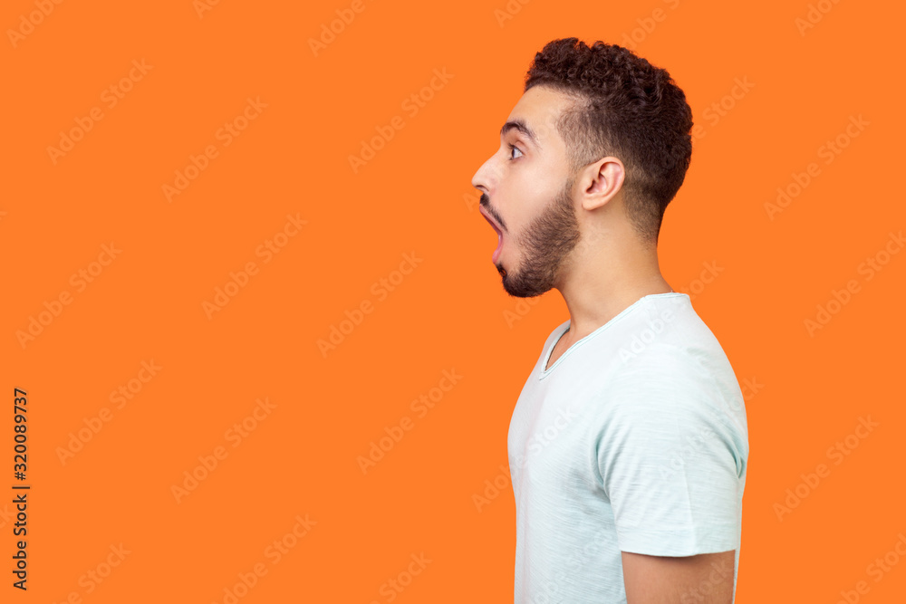 Side view portrait of surprised brunette man with beard in white t ...