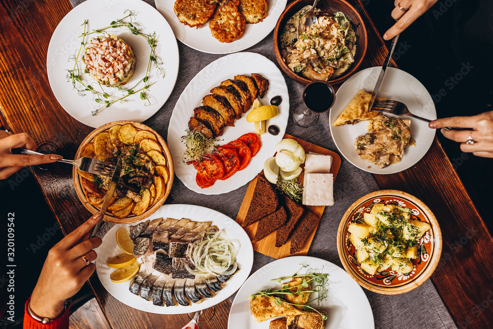 large wooden table with mouthwatering national Russian dishes. The ...