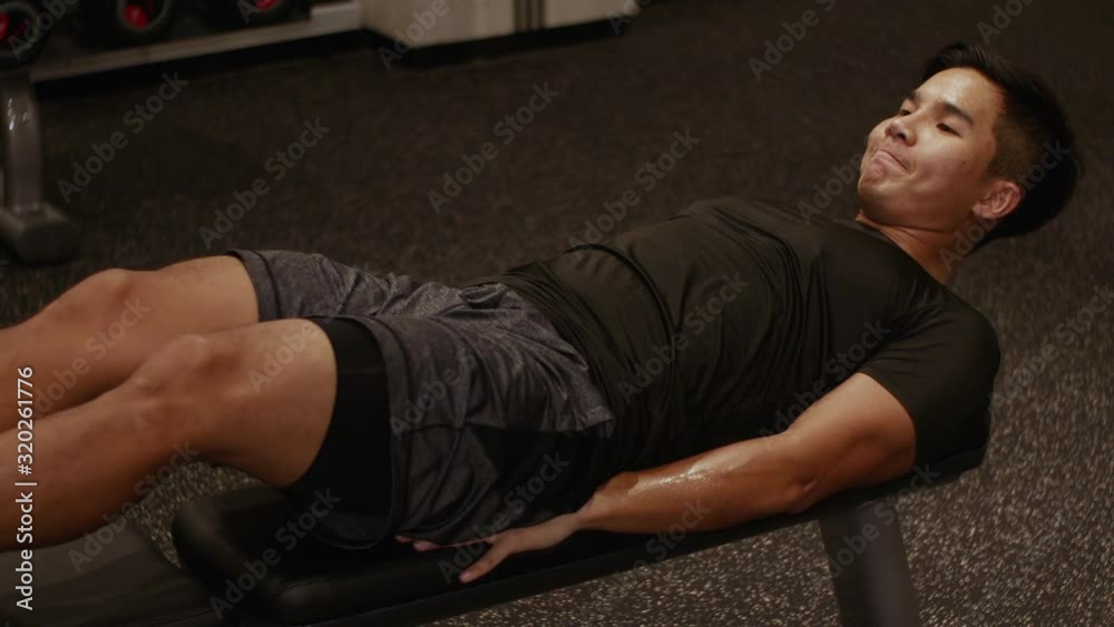 4k Asian male doing abs workout on the black bench at the gym, leg ...