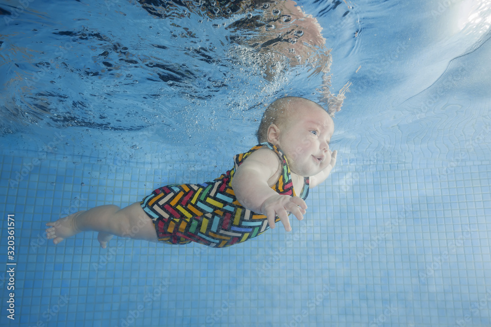 Cute chubby little girl in a swimsuit dives underwater in a swimming ...