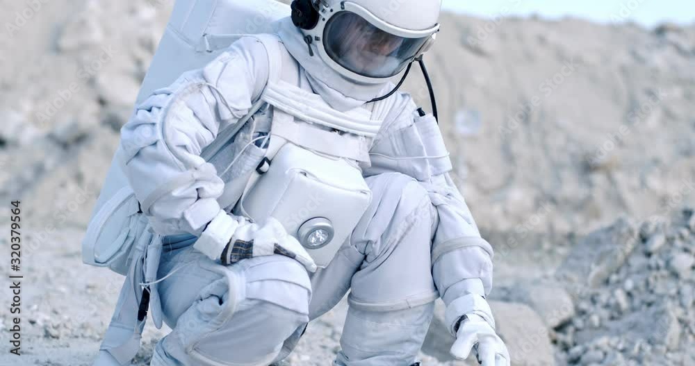 Cosmonaut in the white space armor and helmet on his head touching ...