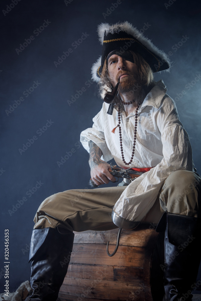 Pirate filibuster sea robber in suit with gun and saber sits on barrel ...