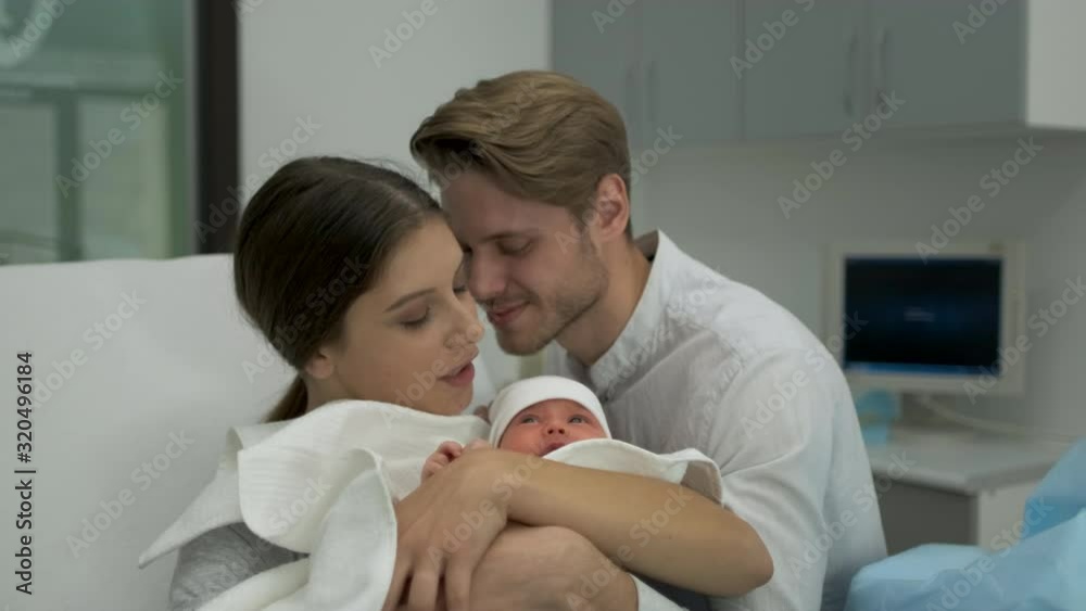 Happy family. Newborn baby resting in mother and father arms. Parents right after delivery in ...