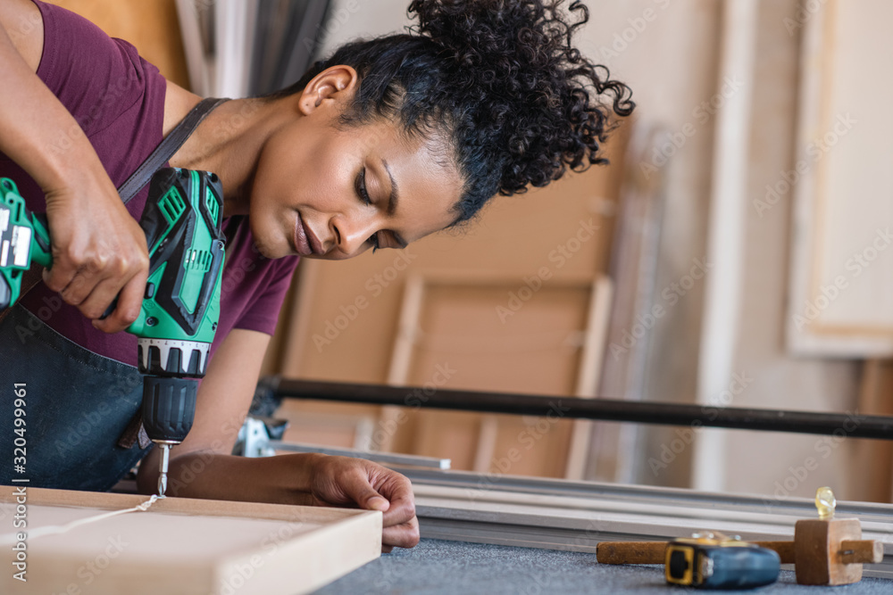 Woman assembling a frame using a drill in her workshop Stock Photo ...
