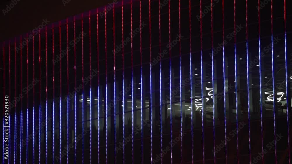 Flashing led strips at night on the wall of the building's facade with ...