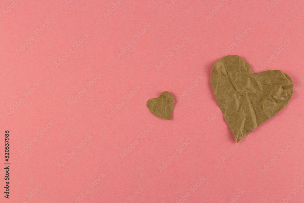 crumpled paper in the shape of two hearts, small and large, on a pink ...