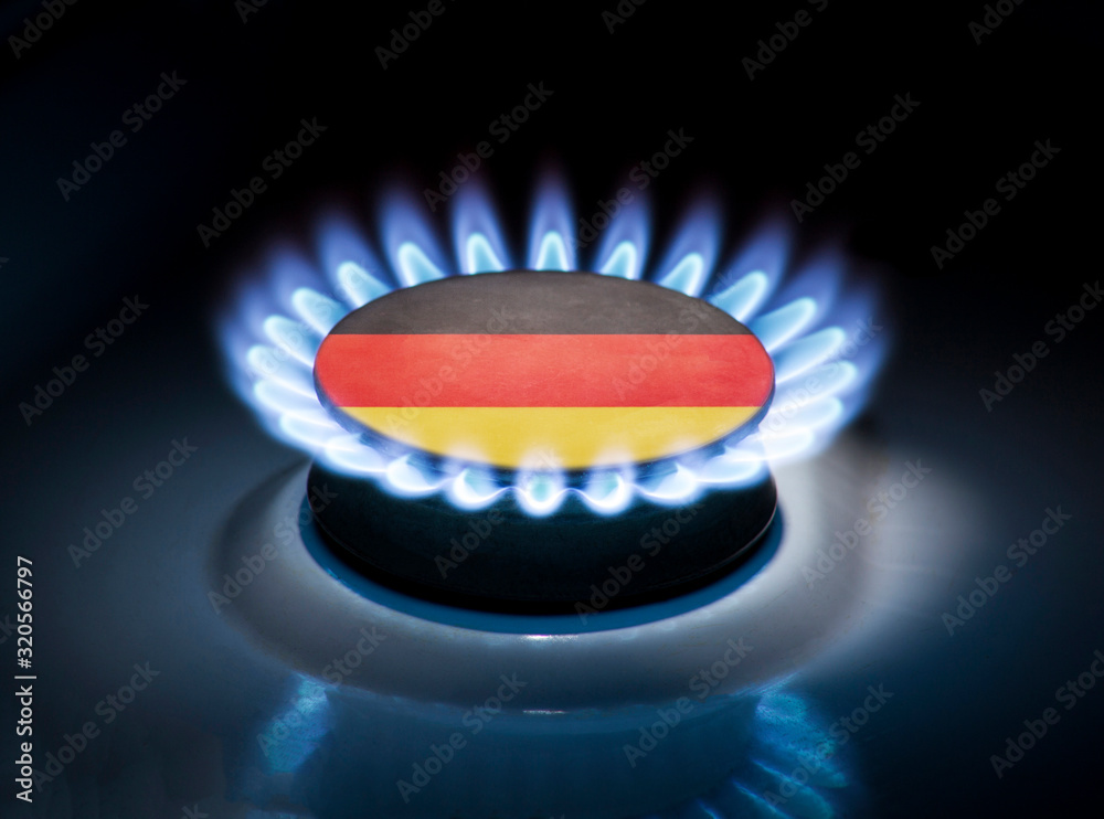 Burning gas burner of a home stove in the middle of which is the flag ...