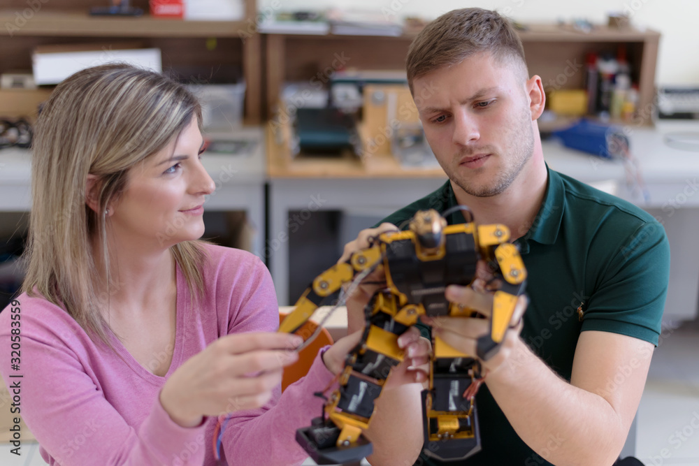 Scientists engineers designing small human robot, setting artificial ...