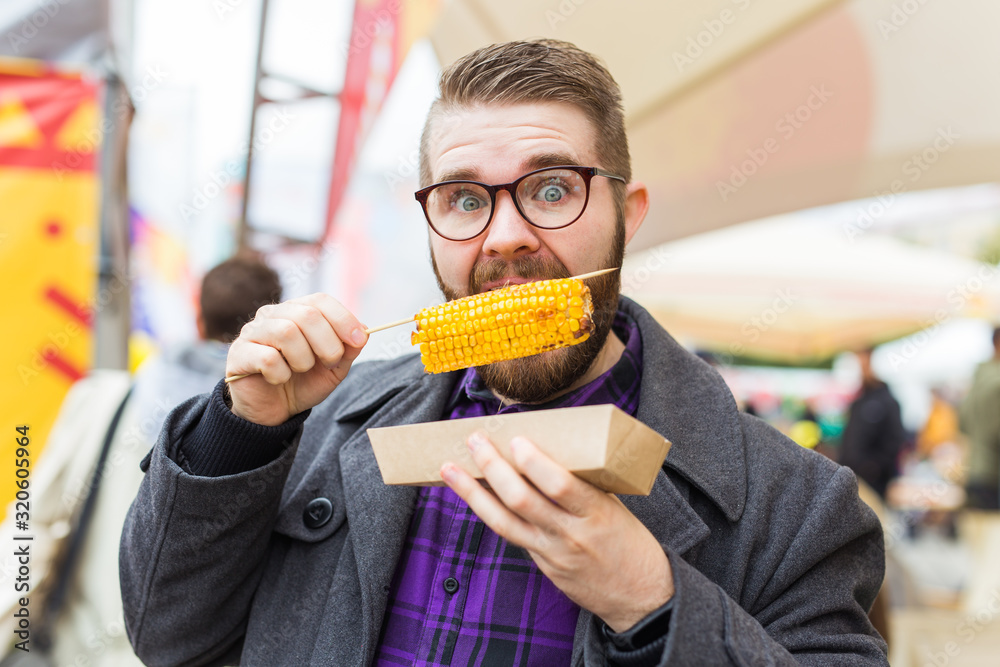 Vegetarian and meal concept - Handsome man eating street food corn at ...