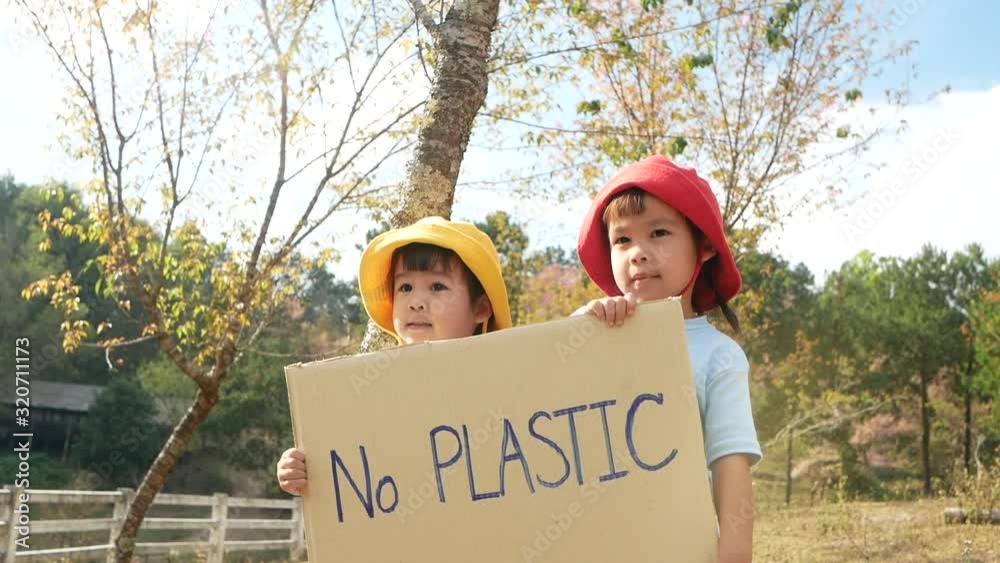 Two little child girl siblings holding "No Plastic" Poster showing a ...