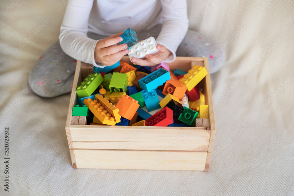 Little girl cleaning up the toy box at home. Child's space organization ...