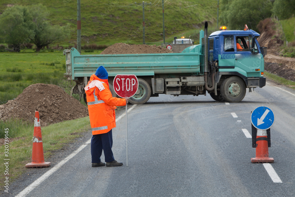 Man with stop sign at roadworks. Flagman. Traffic warden. Truck turning ...