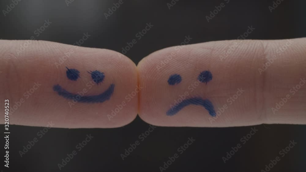 Two fingers with happy and sad smileys on finger pads meeting each ...