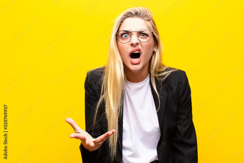 young pretty blonde woman looking angry, annoyed and frustrated ...