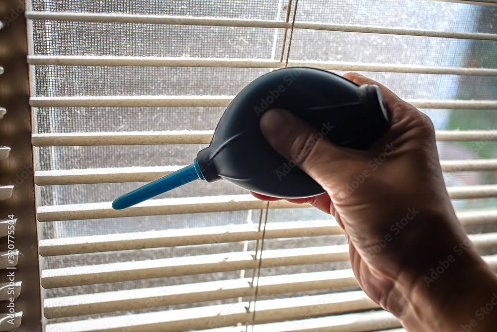 Foto Stock Woman's right hand squeezing blue blower for cleaning dust ...