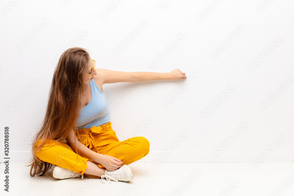 yound blonde woman standing and pointing to object on copy space, rear ...