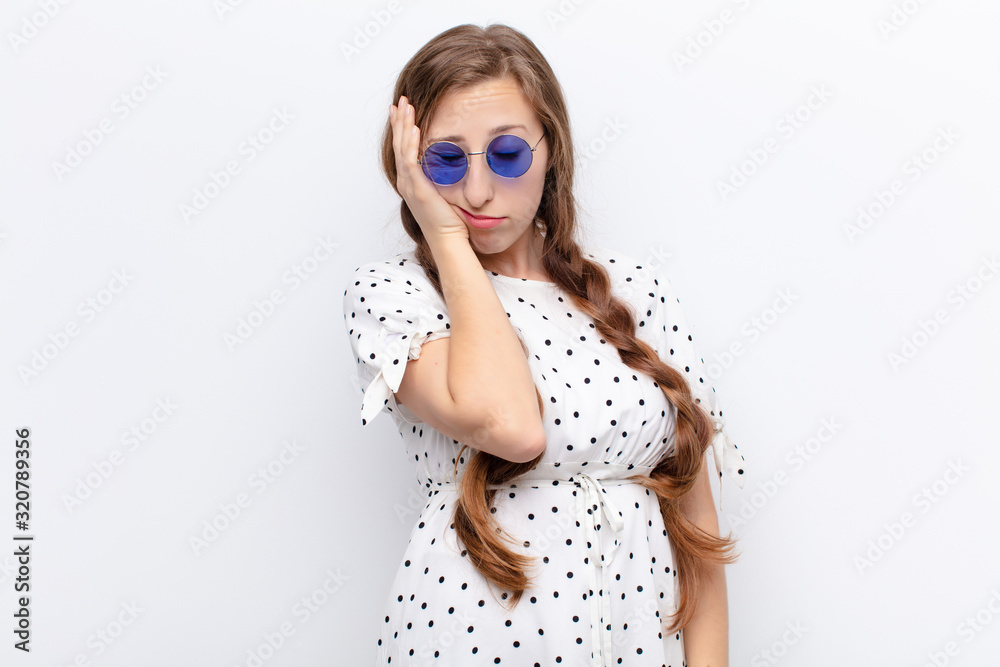 yound blonde woman looking sleepy, bored and yawning, with a headache ...