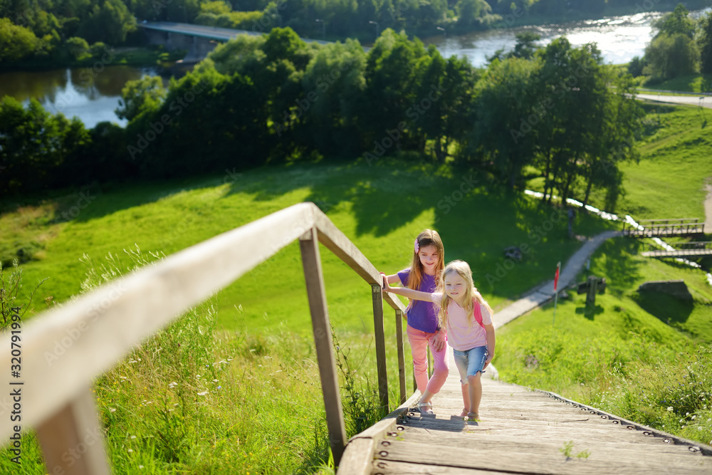 Two little girls exploring famous Merkine mound with green trees and ...