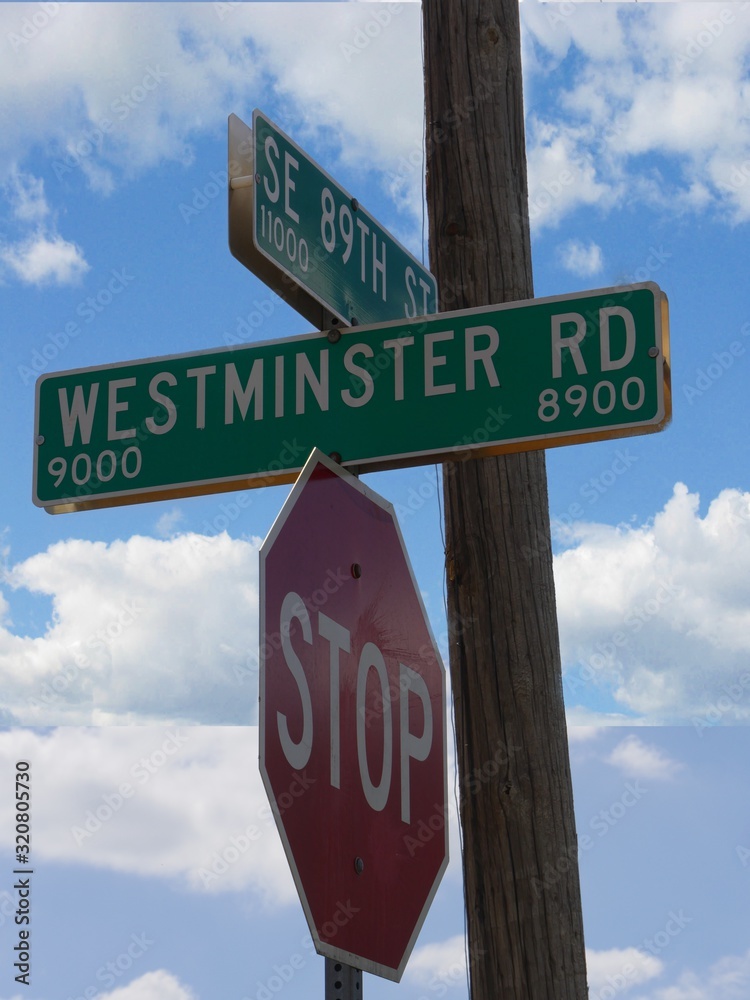 Stop sign and street signs, with blue and white skies in the background ...