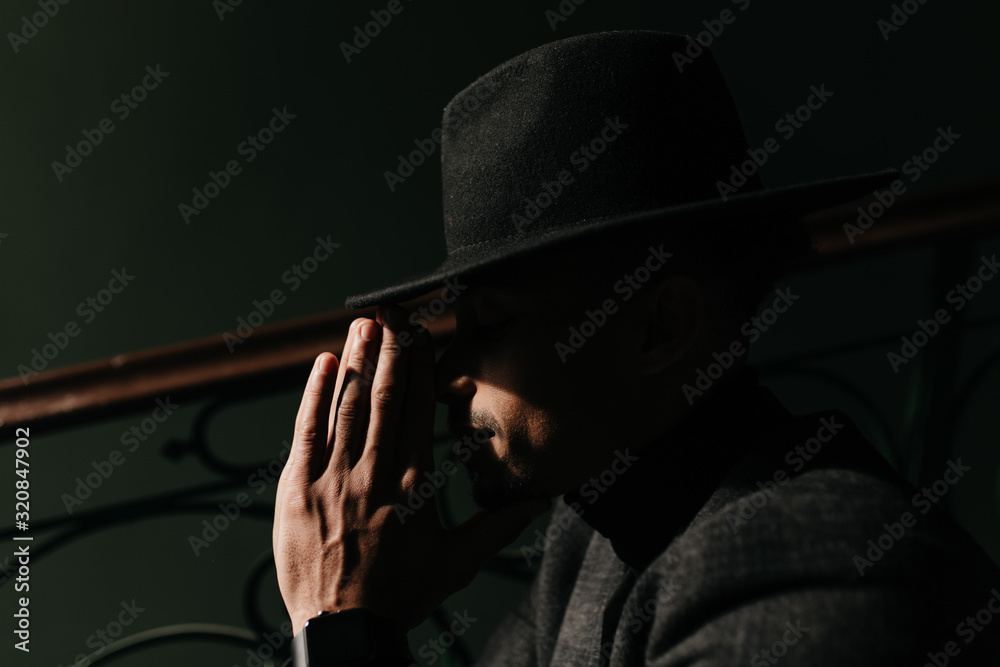 Well-dressed stylish man thinking about something in dark room ...