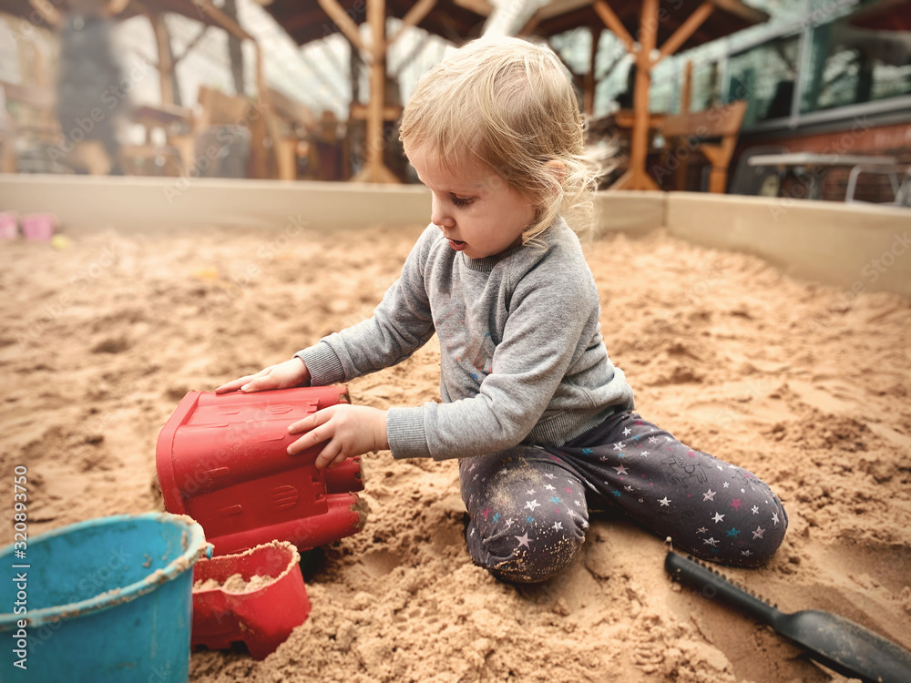 Little girl building a sandcastle in the sand - Little girl building a ...