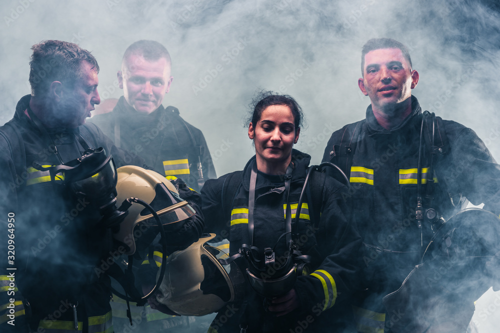 Team of firefighters standing the middle of the fire extinguisher's ...