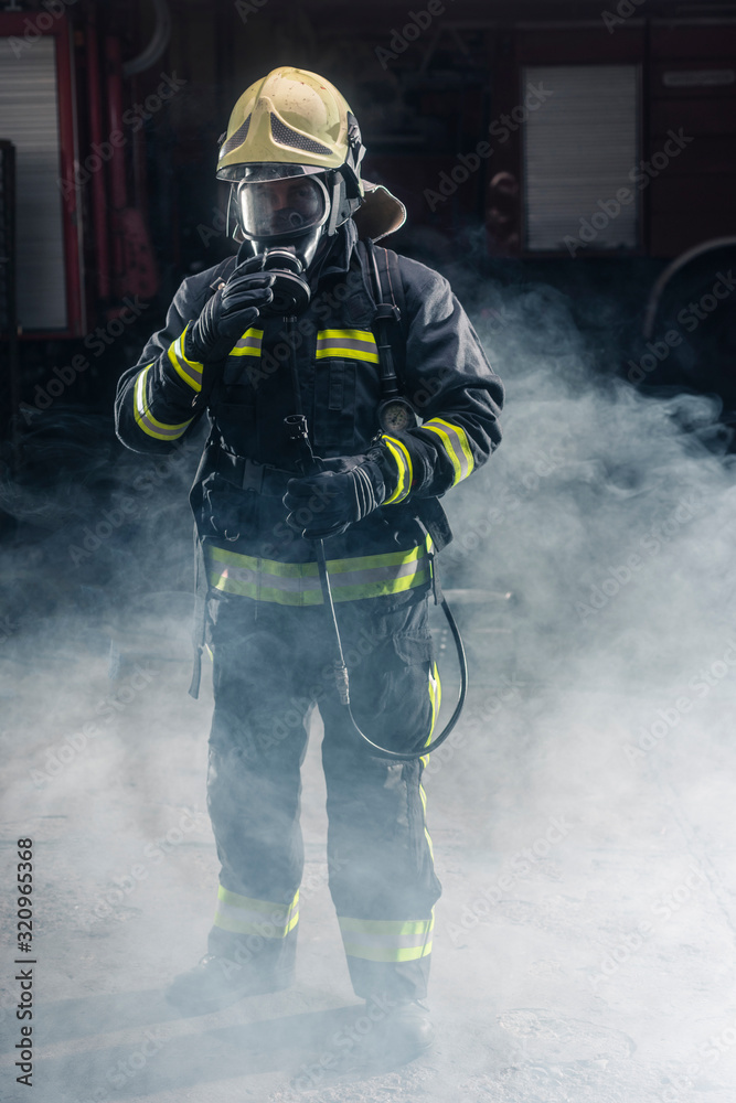 Portrait of a fireman wearing firefighter turnouts and helmet. Dark ...