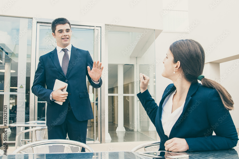 Business people gesturing and saying goodbye to each other outdoors ...