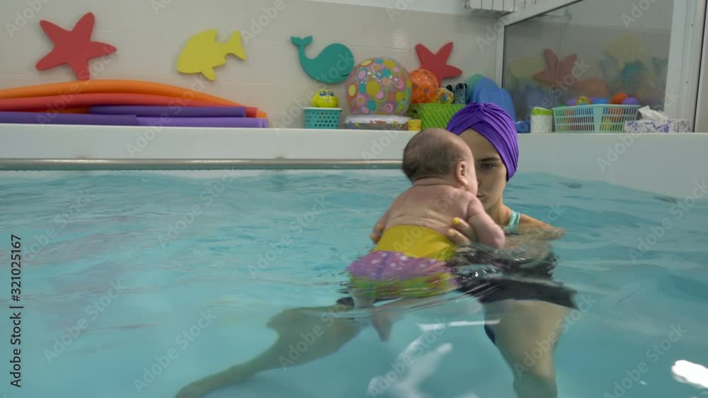 Infant swimming in the children's pool. Baby swims face to face in mom ...